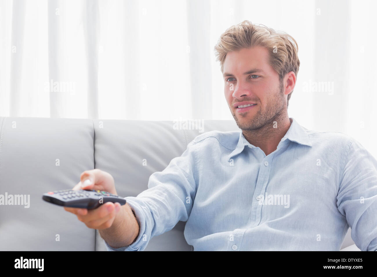 Man changing tv channel sat on the couch Stock Photo - Alamy