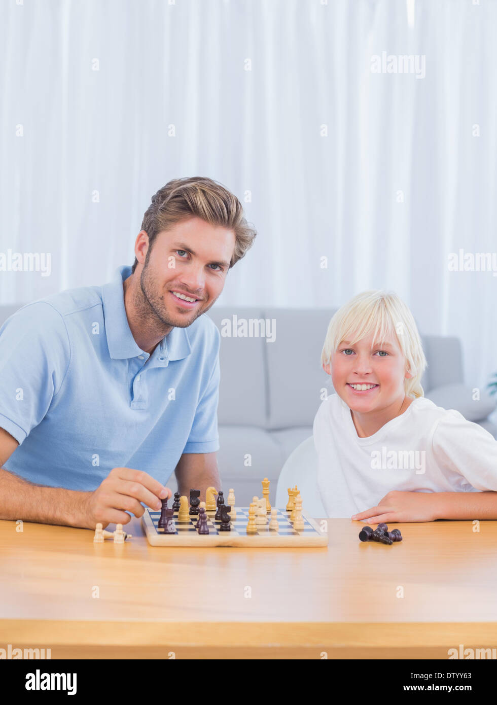 Smiling father playing chess with his son Stock Photo - Alamy