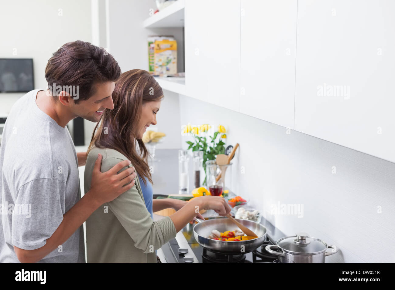 Man looking at his wife cooking Stock Photo - Alamy
