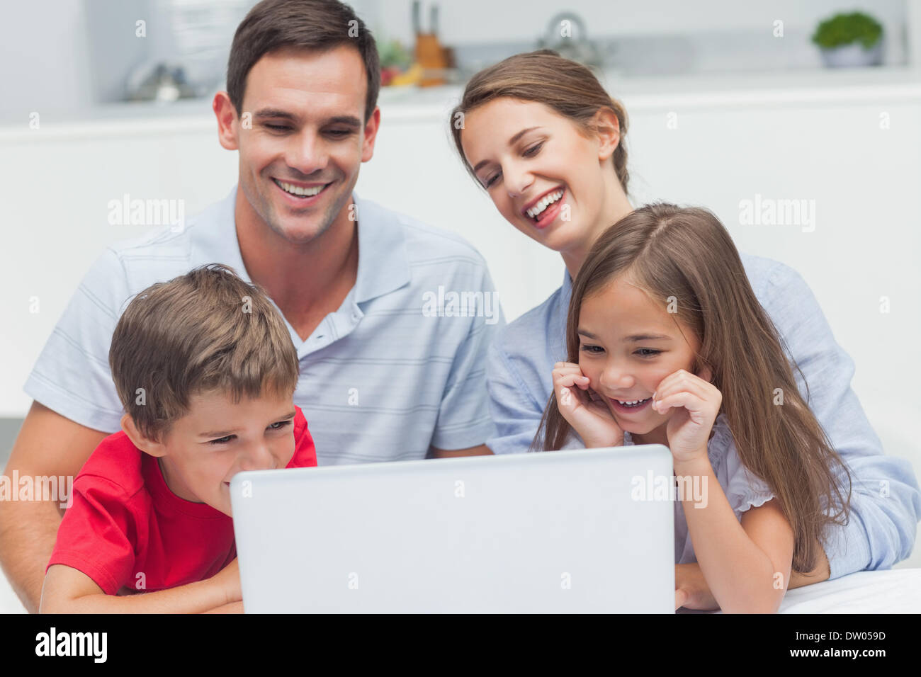 Cheerful parents and children using a laptop Stock Photo - Alamy