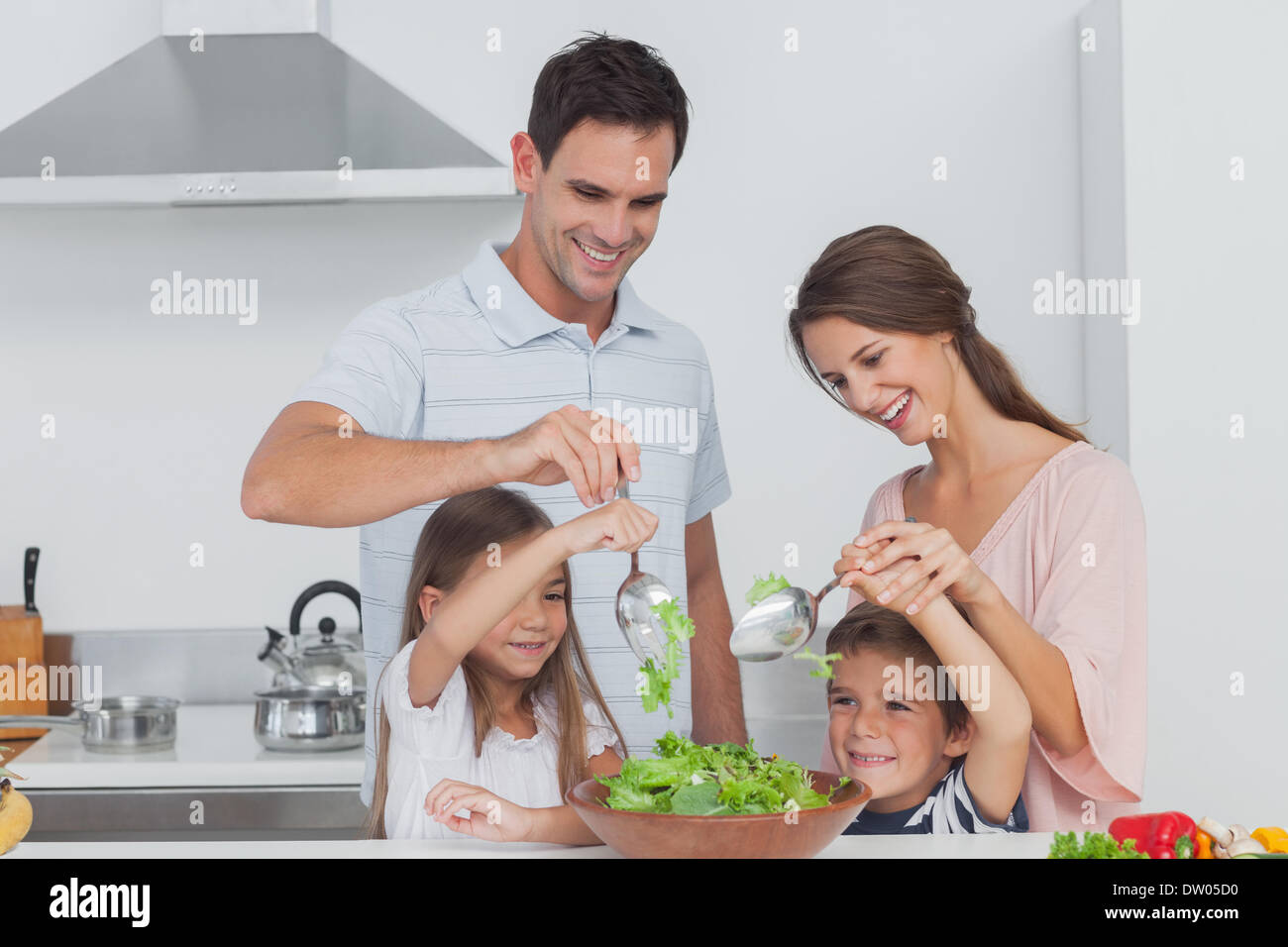 Family mixing a salad together Stock Photo - Alamy