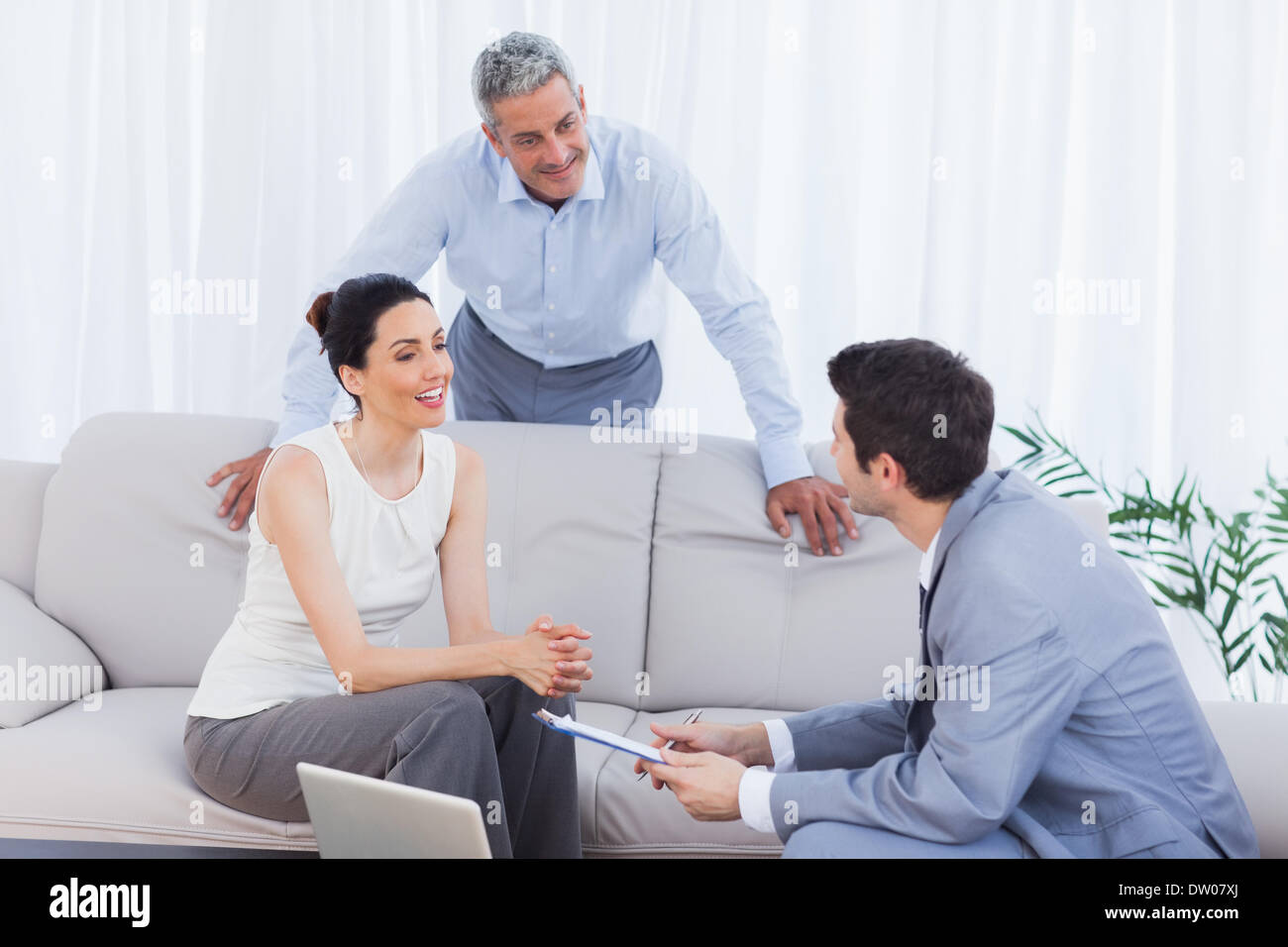 Salesman talking with customers on couch Stock Photo - Alamy