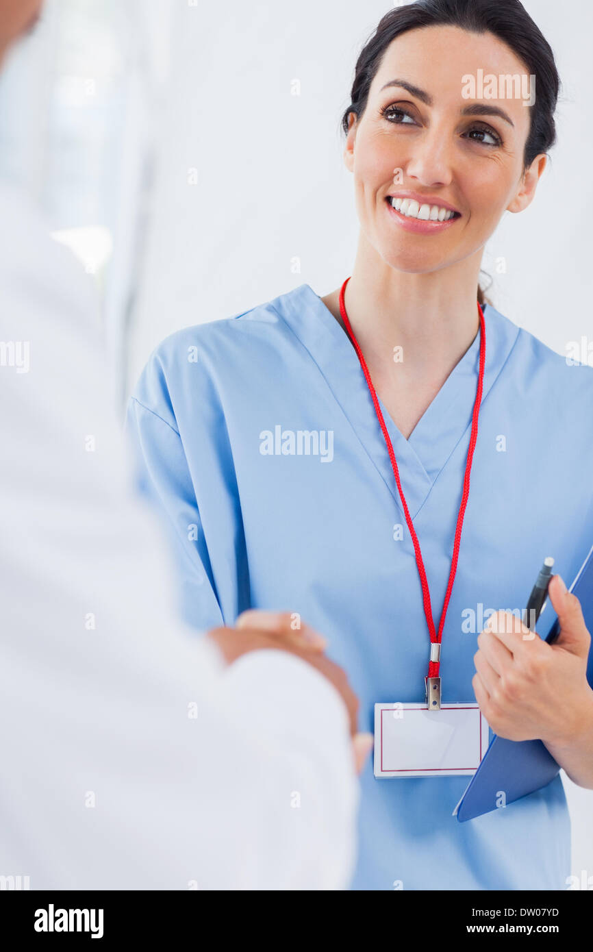 Happy nurse shaking hands with doctor Stock Photo - Alamy