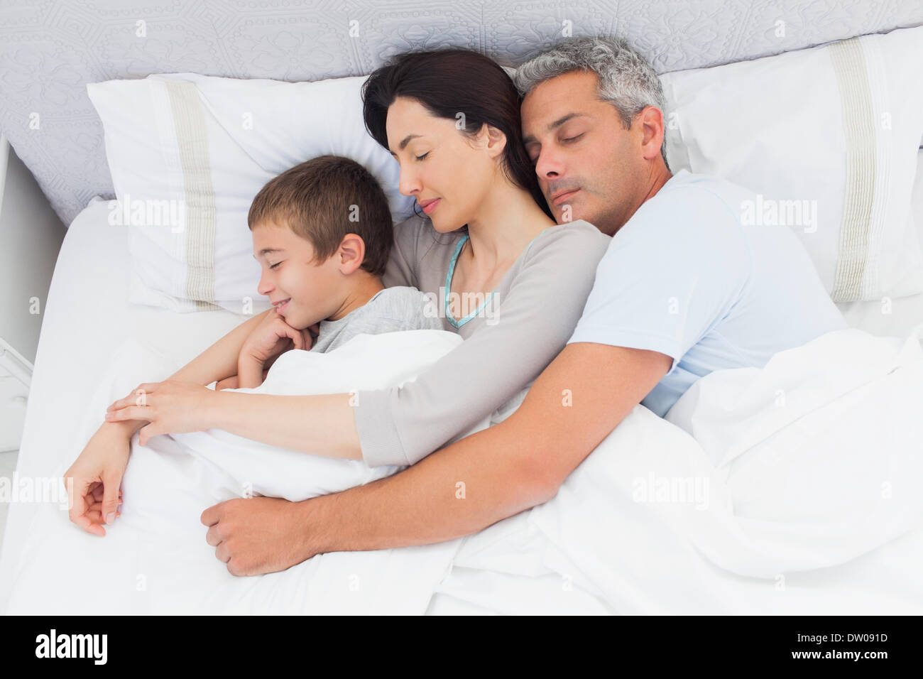 Parents sleeping with their son in bed Stock Photo - Alamy