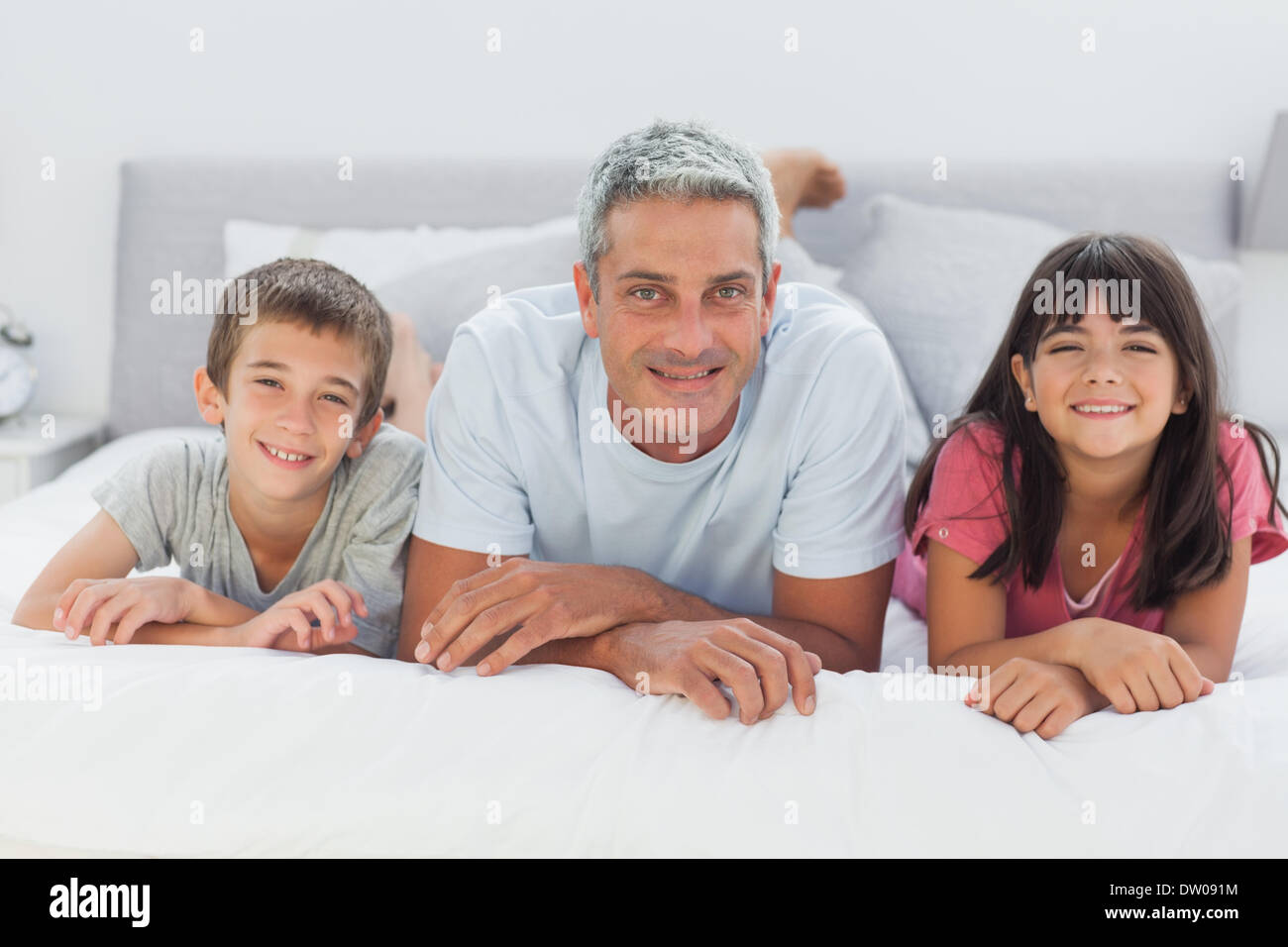 Father with his children lying on bed Stock Photo - Alamy