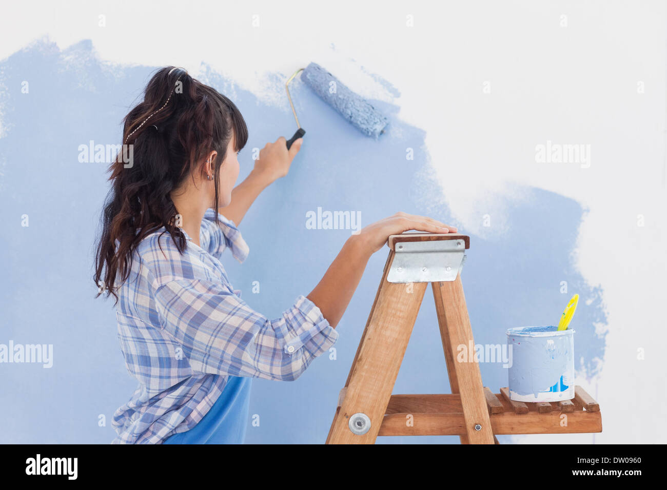 Woman using paint roller to paint wall Stock Photo - Alamy