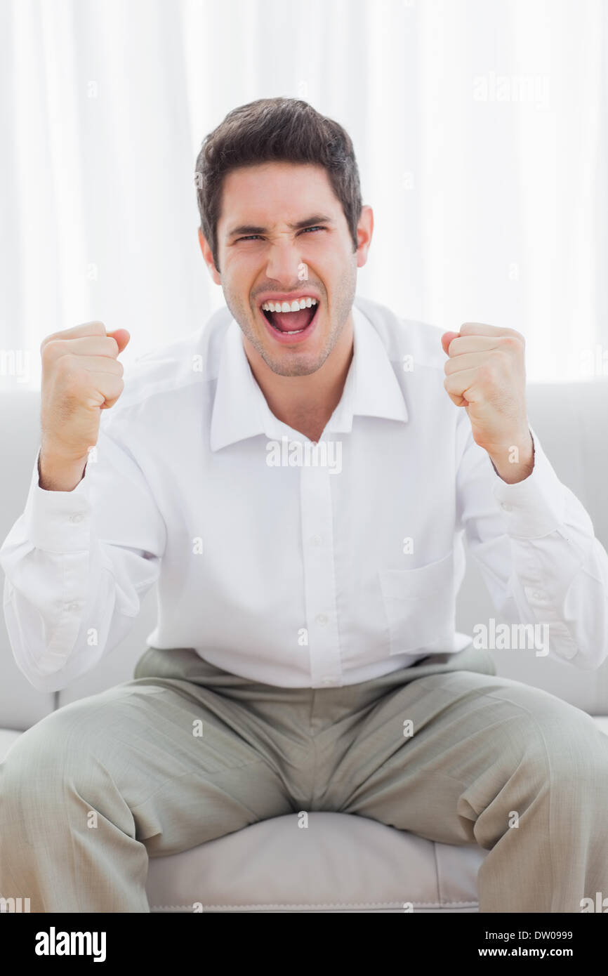 Happy man sitting on sofa has success Stock Photo - Alamy