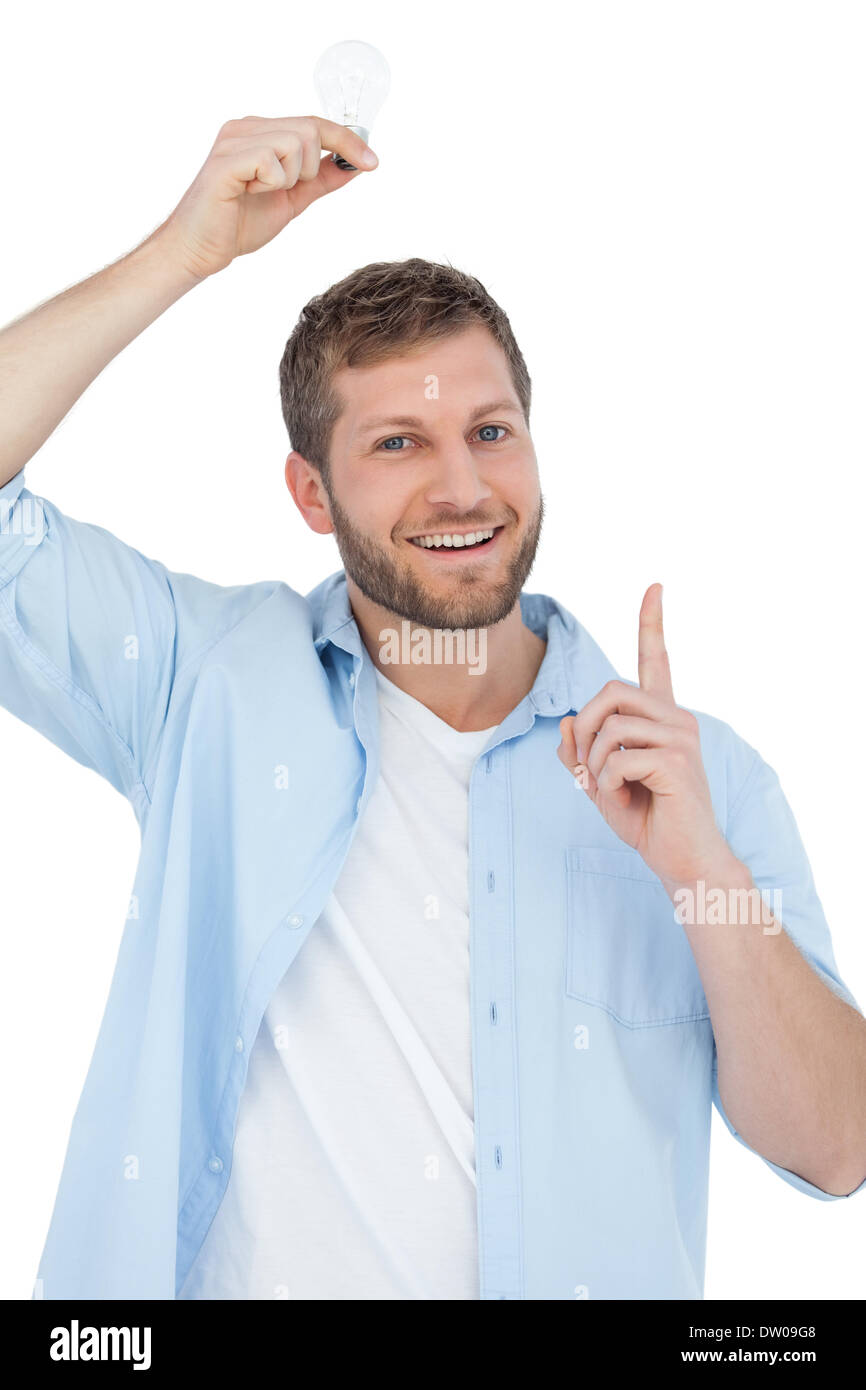 Smiling model holding a bulb above his head Stock Photo - Alamy