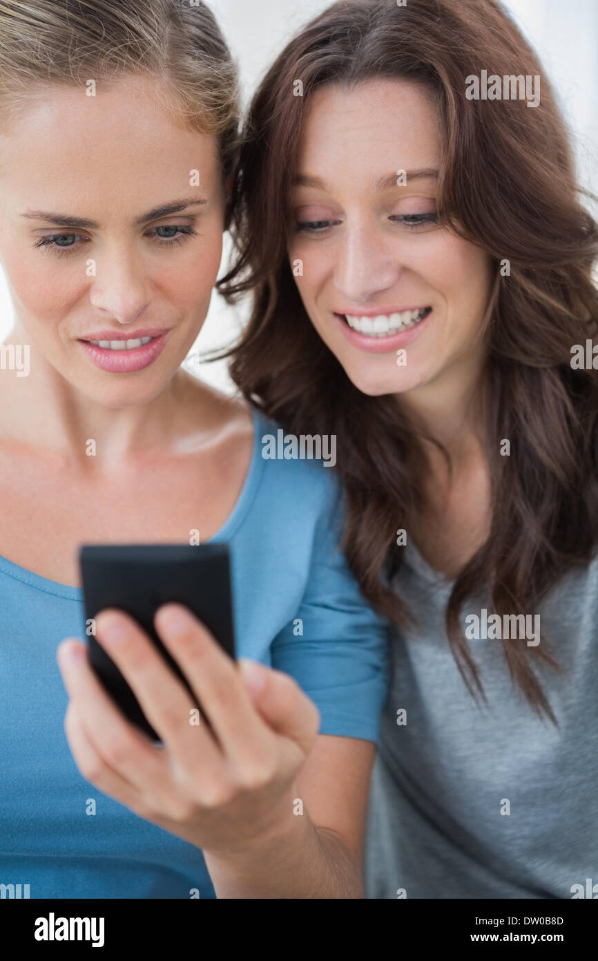 Smiling friends looking at mobile phone Stock Photo - Alamy