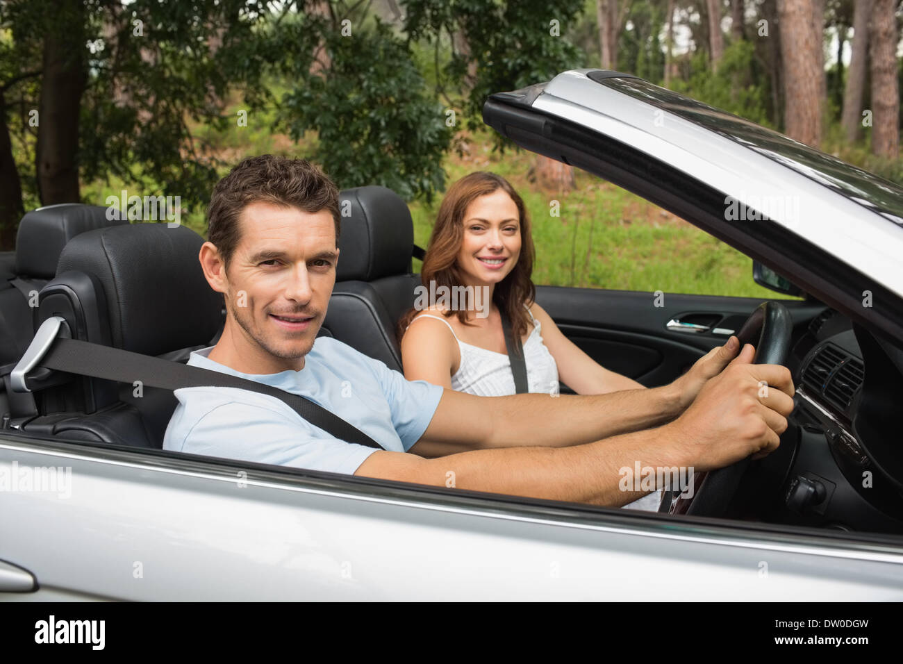 Happy couple driving in a silver convertible Stock Photo - Alamy