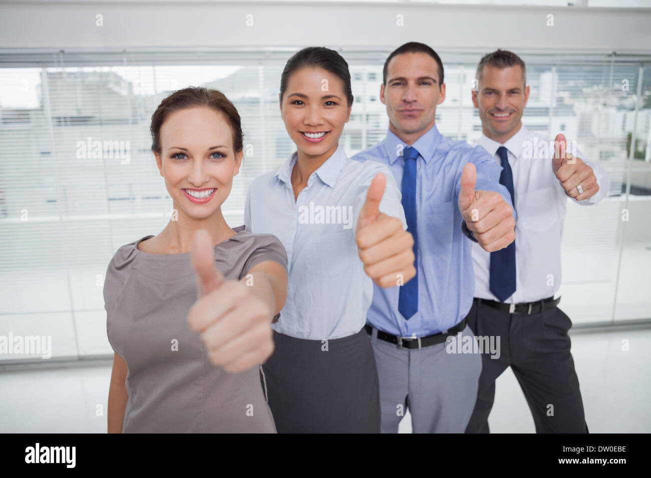 Smiling work team giving thumbs up Stock Photo - Alamy