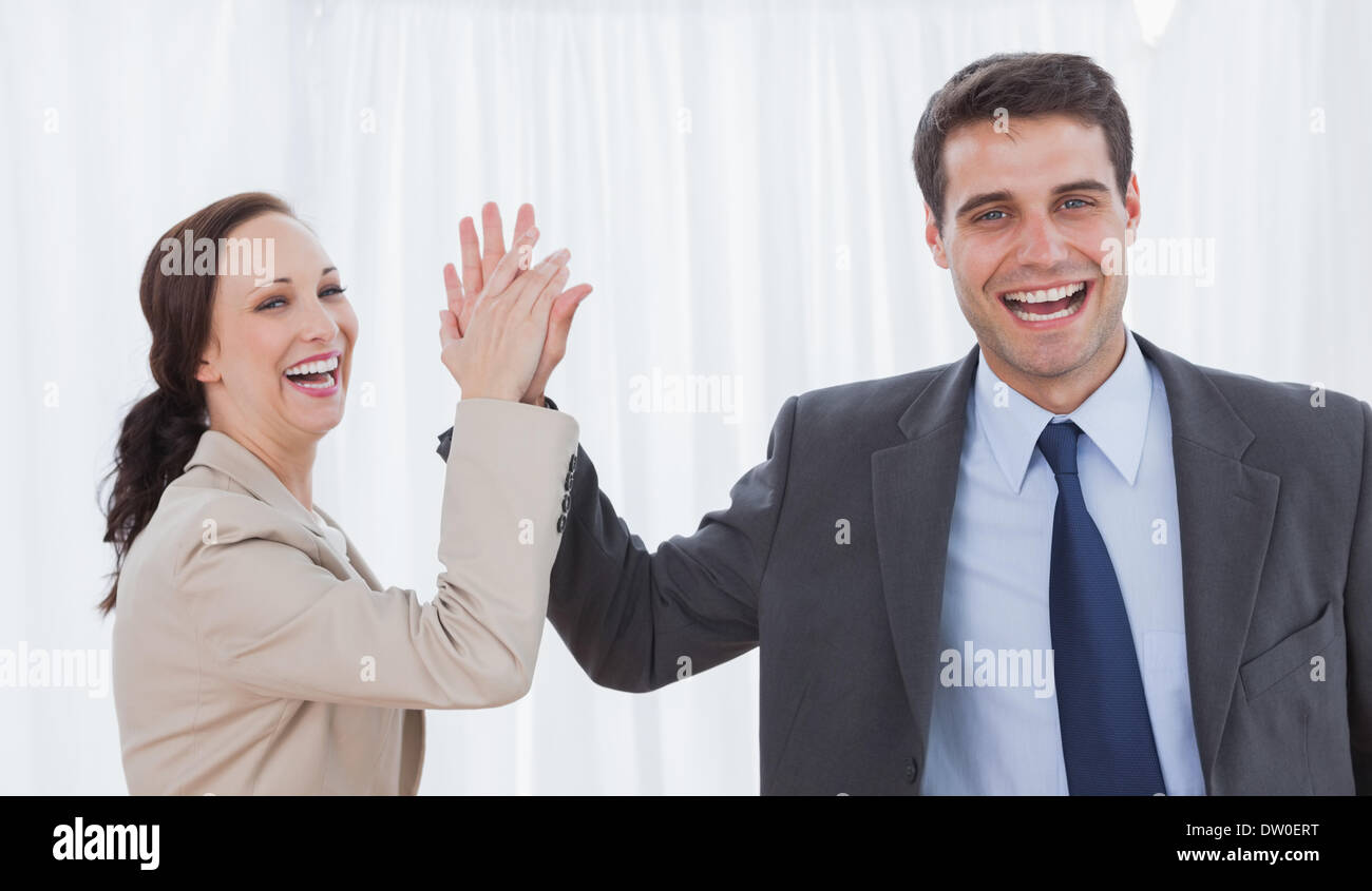 Cheerful workmates doing high five Stock Photo - Alamy