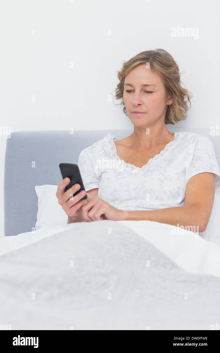 Blonde woman sending text message in bed Stock Photo - Alamy