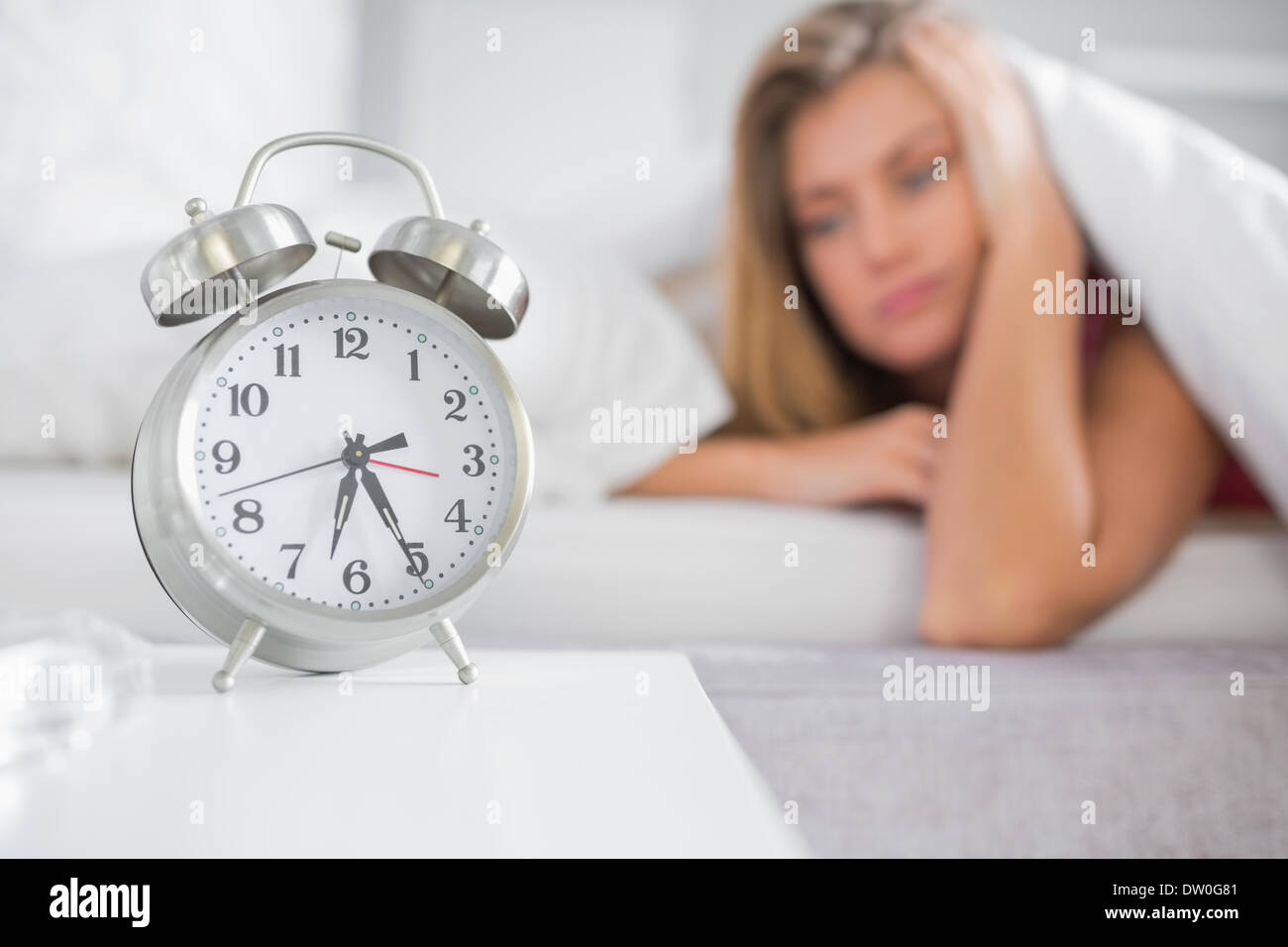 Tired blonde staring at her alarm clock Stock Photo - Alamy