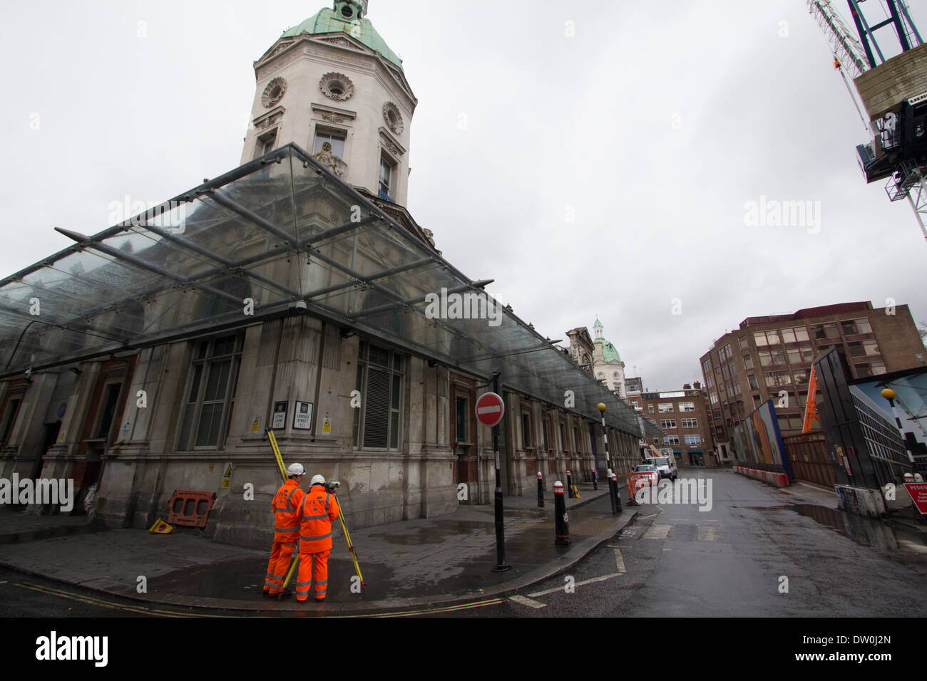 Surveyors wearing fluorescent high-visibility clothing use a theodolite ...