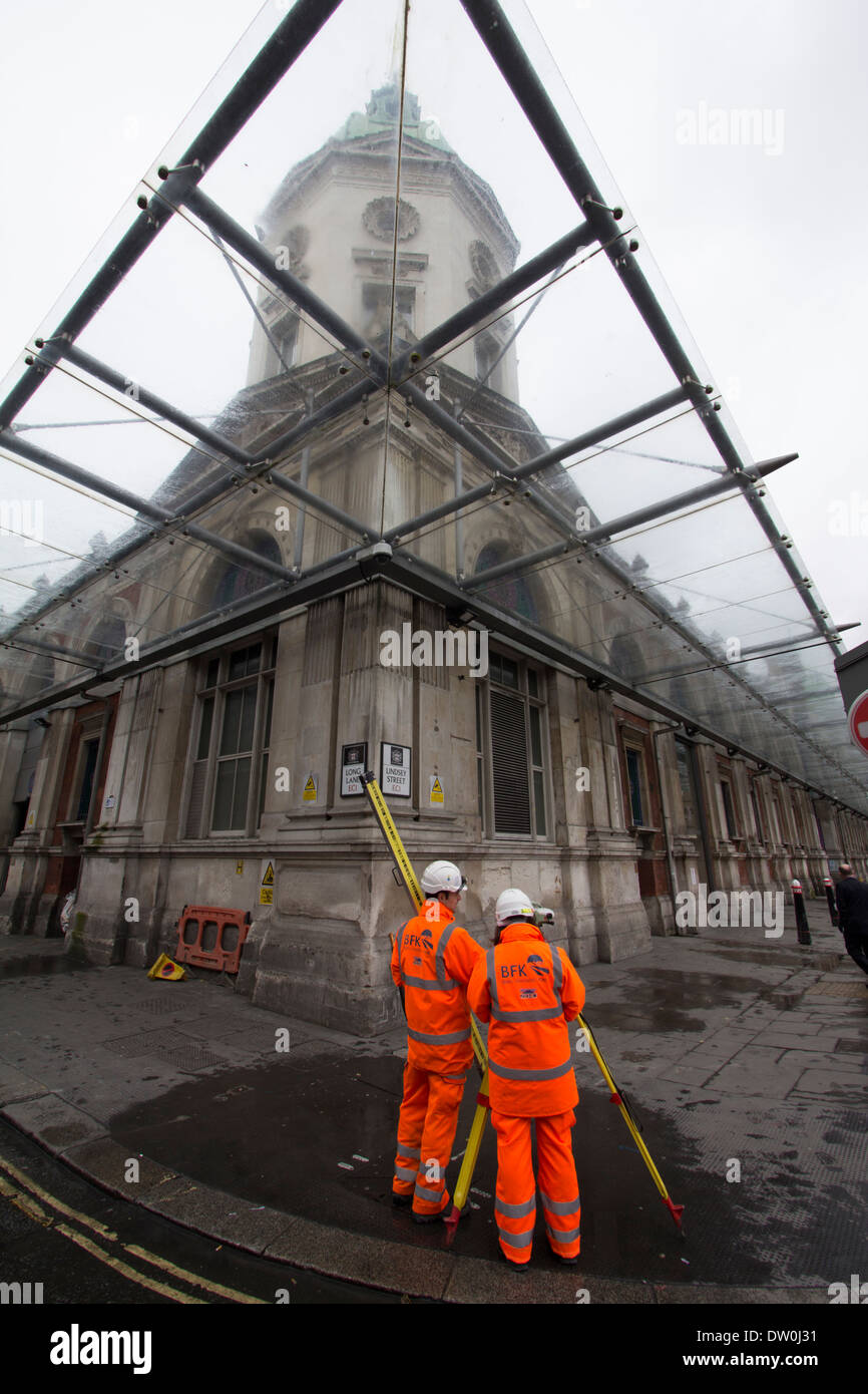 Surveyors wearing fluorescent high-visibility clothing use a theodolite ...