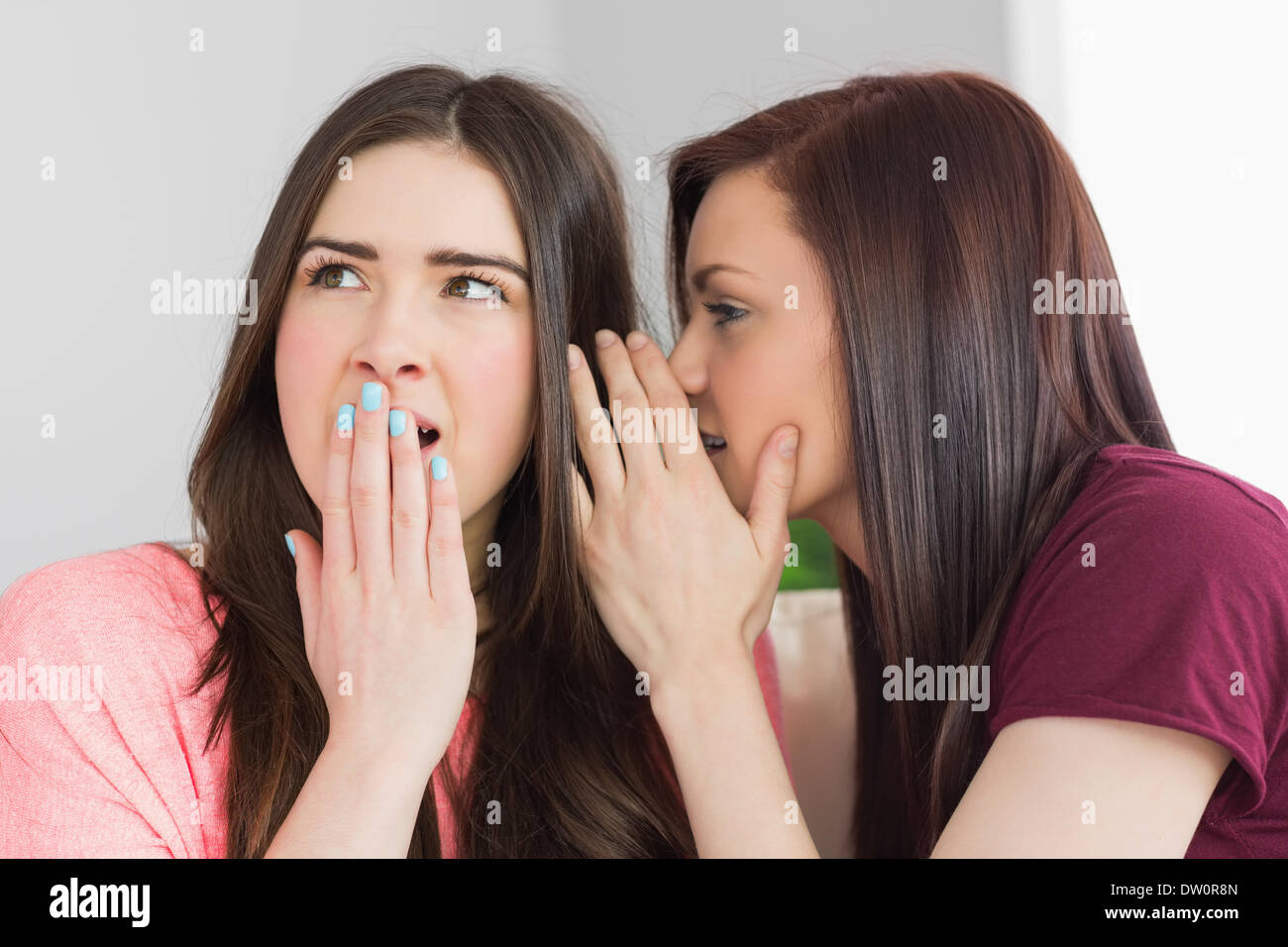 Two smiling girls sharing secrets Stock Photo - Alamy