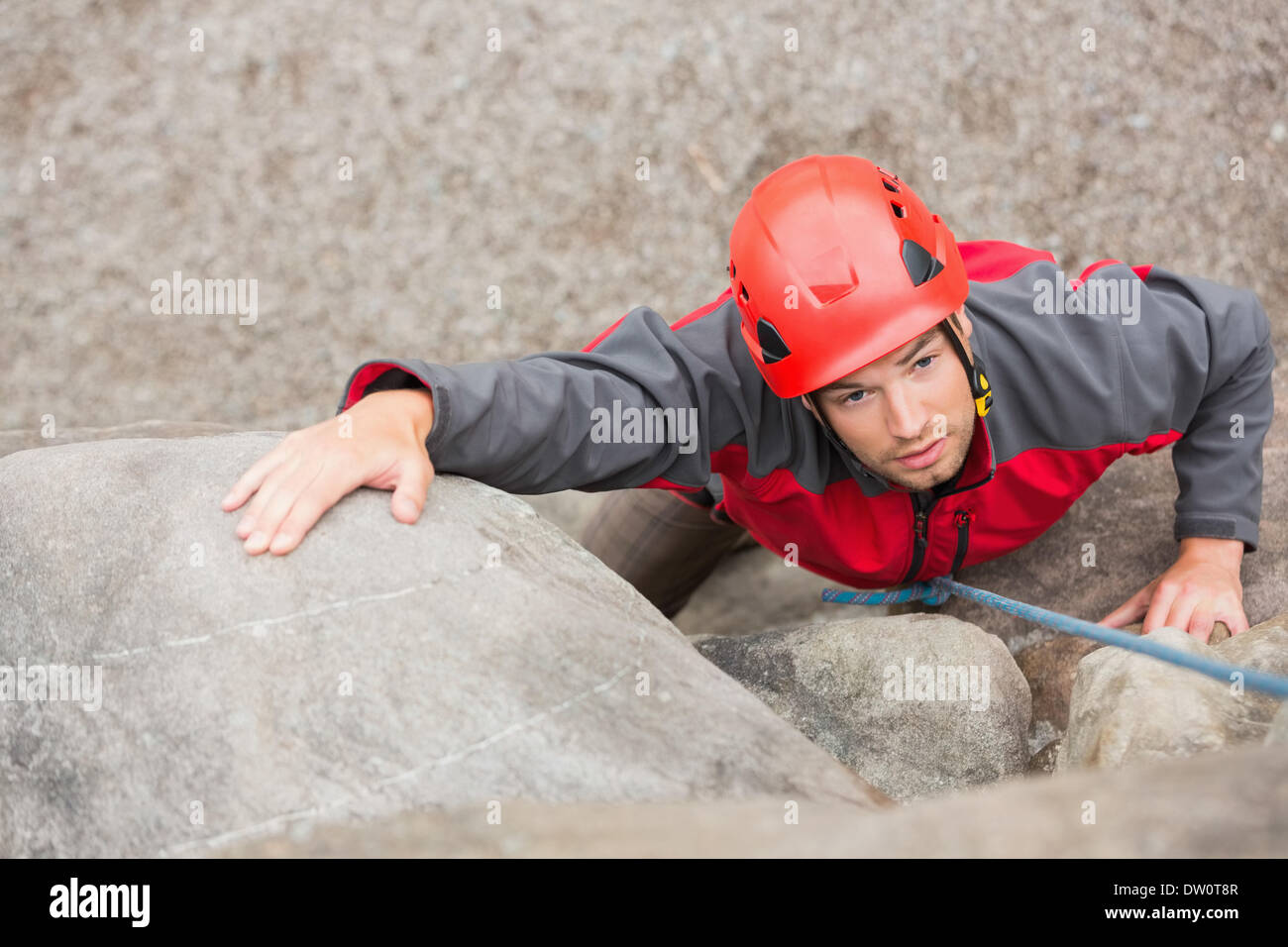 Determined man climbing rock face Stock Photo - Alamy