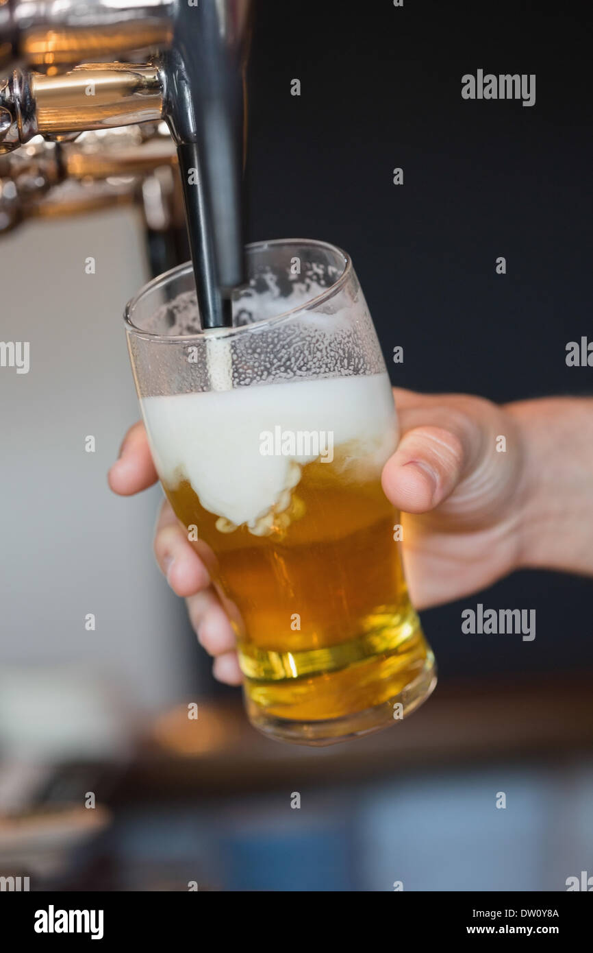 Hand holding glass filling beer Stock Photo - Alamy