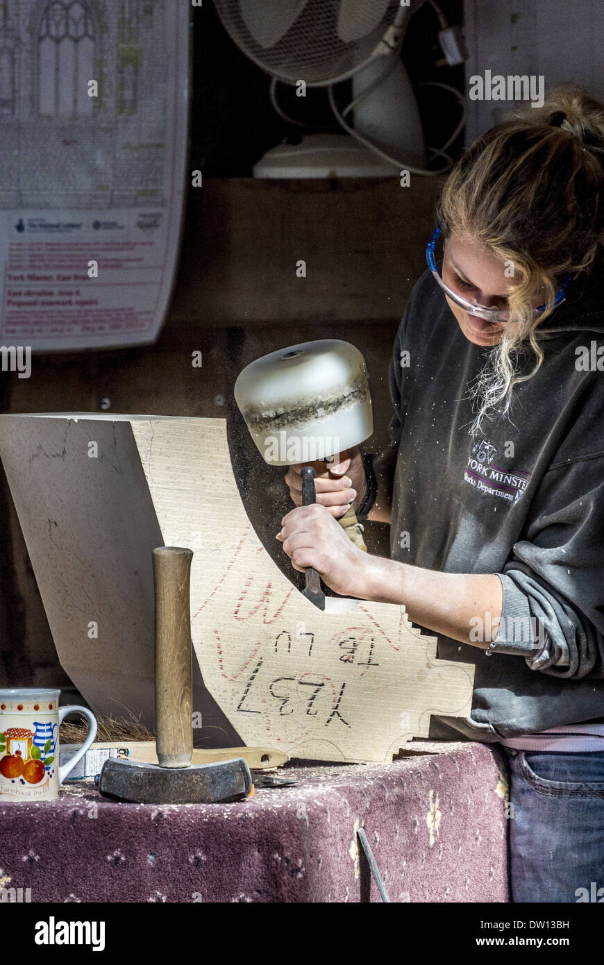 Female stonemason carving block of stone at York Minster stoneyard ...