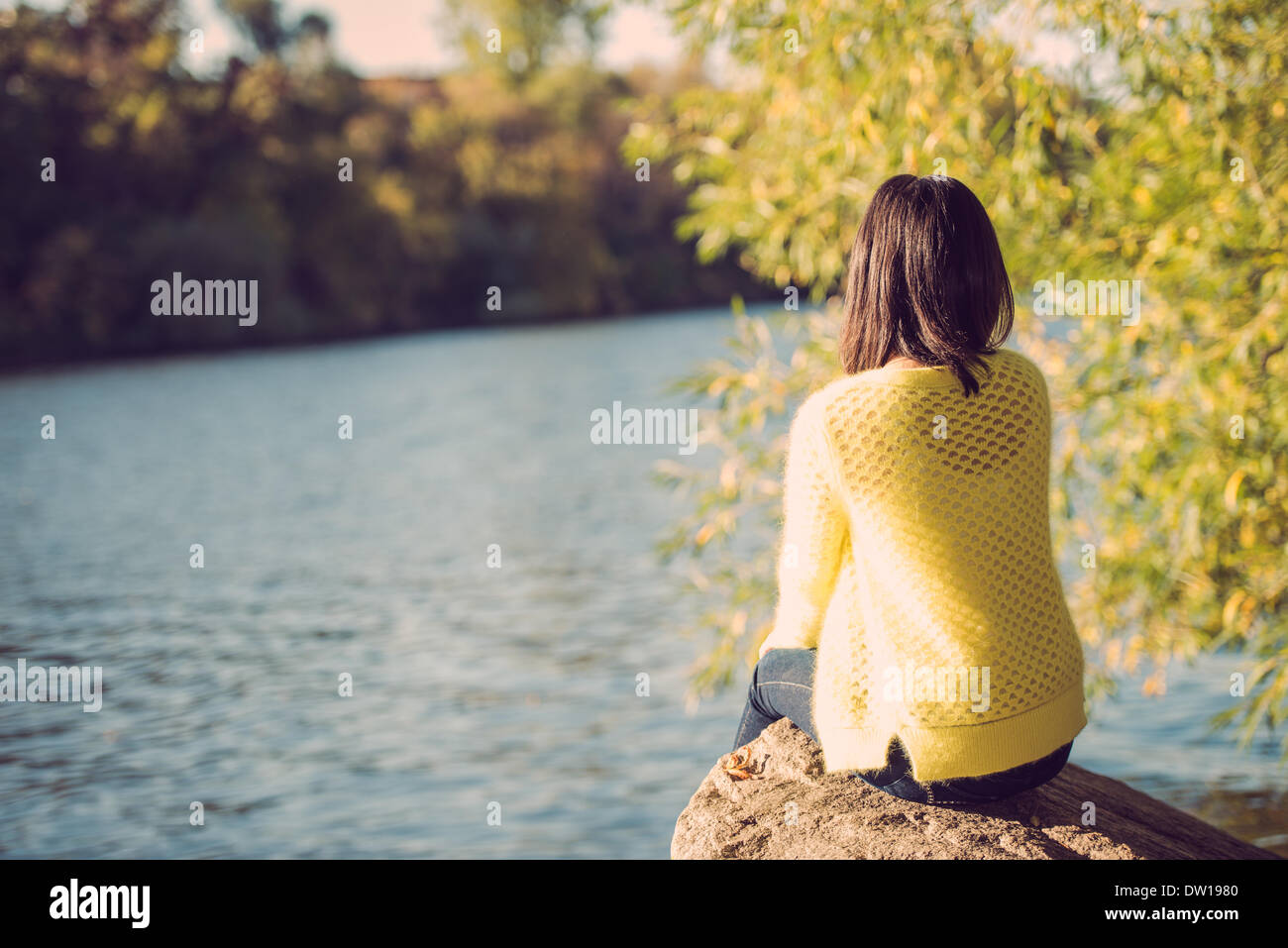 Woman sitting next to a river Stock Photo - Alamy