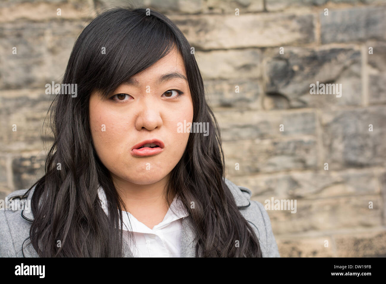 Angry woman by a stone wall Stock Photo - Alamy