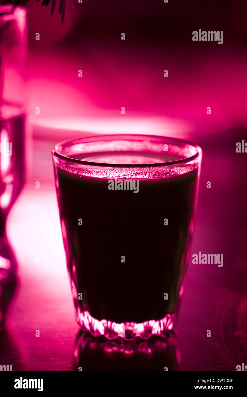 Glass with beverage on red color Stock Photo - Alamy