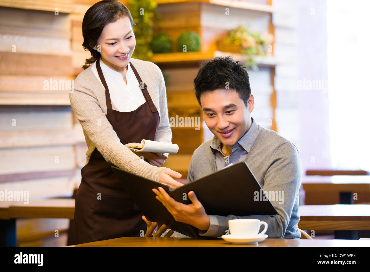 Waitress showing menu to customer Stock Photo - Alamy
