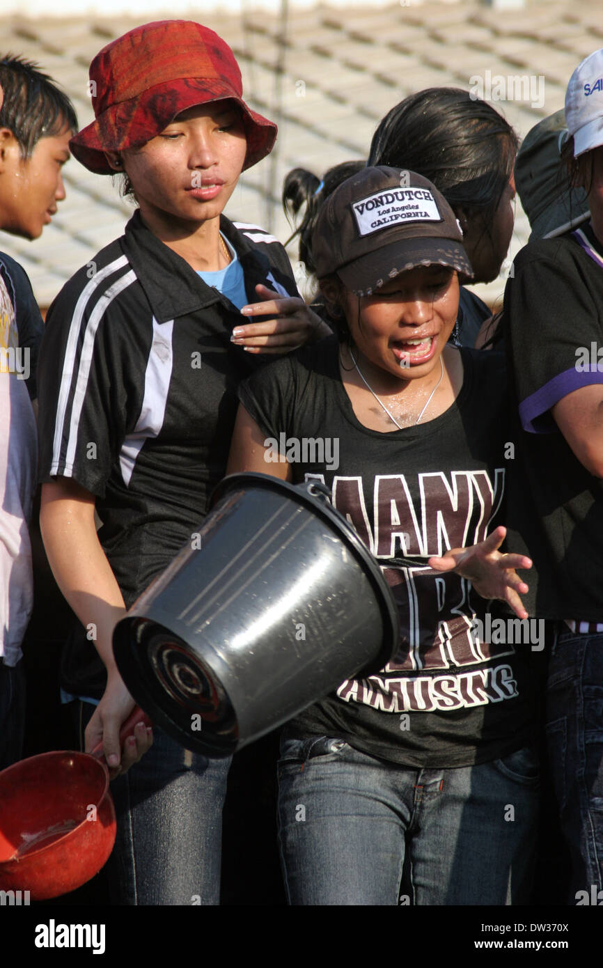 A young woman is holding a bucket as she prepares to throw water during ...