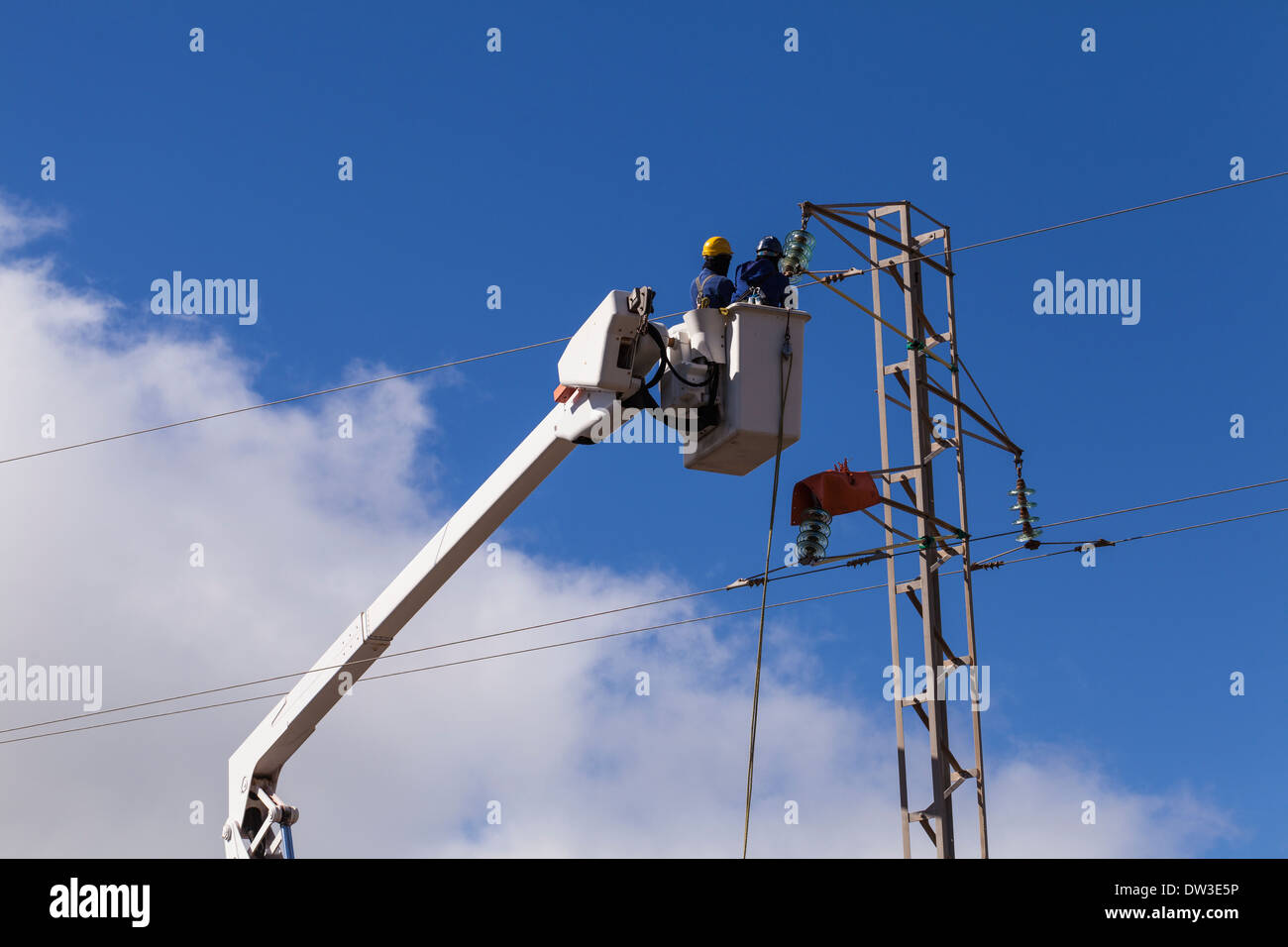 Power workers in a cherry picker working on high tension cables Stock ...