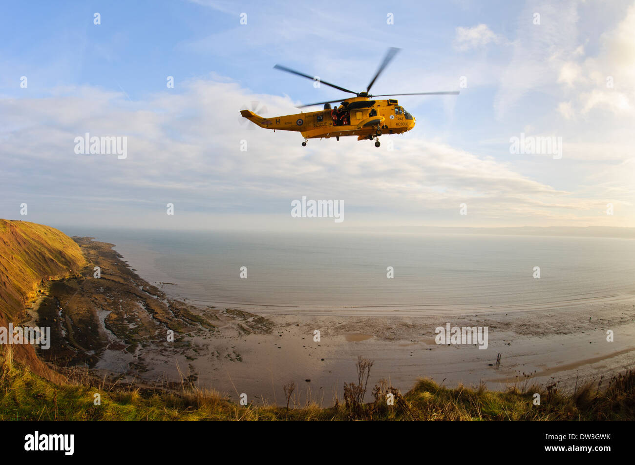 A yellow RAF Rescue helicopter with two crew members standing in the ...