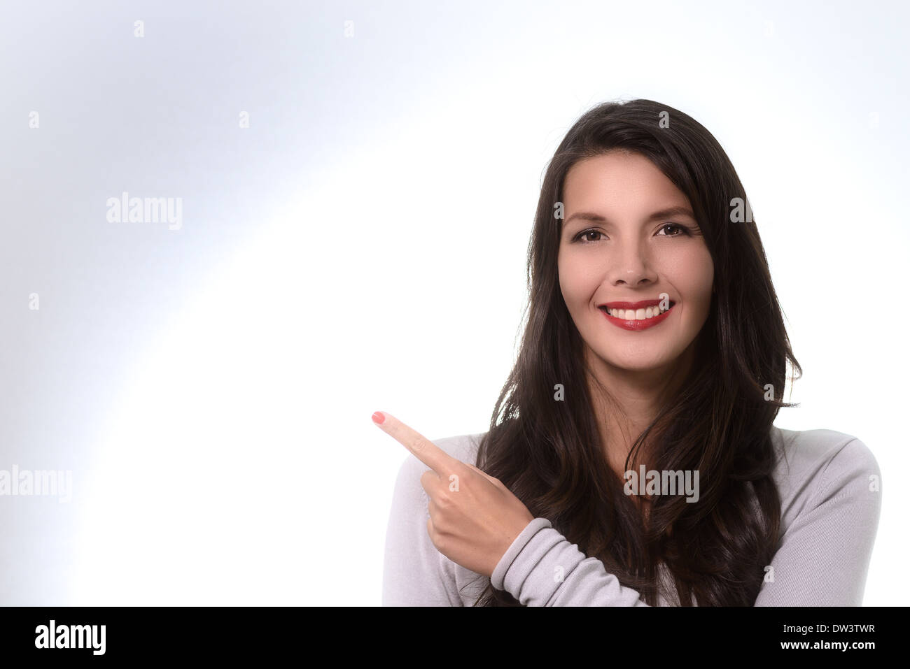 Beautiful stylish woman pointing to copy space with a friendly smile as ...
