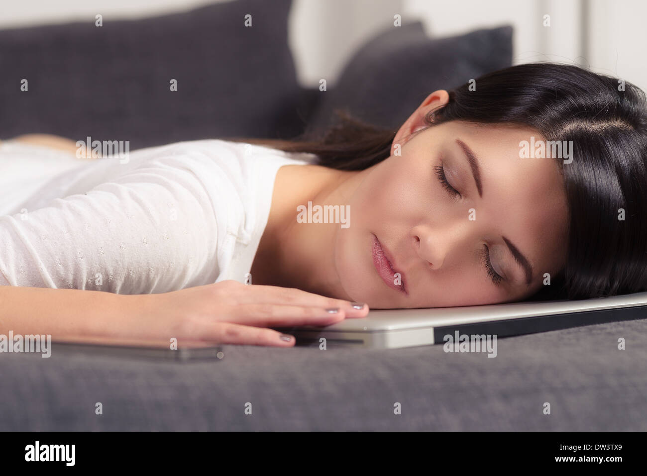 Attractive young woman resting her head on a laptop computer with her ...