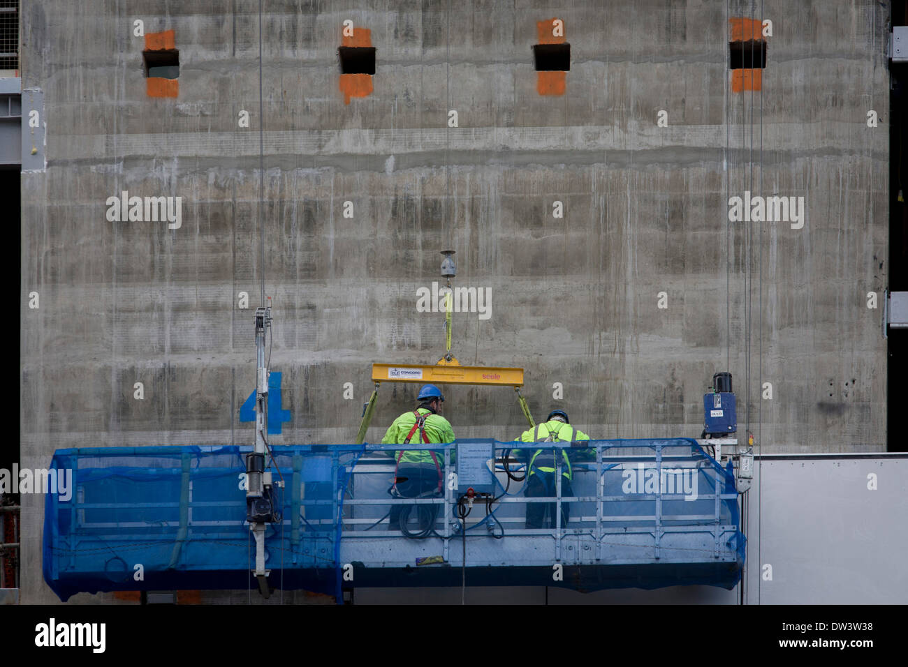Workmen in cradle on concrete wall of construction development in the ...