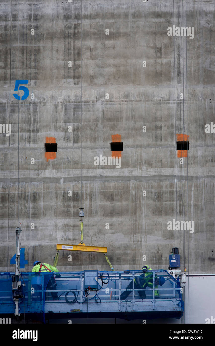 Workmen in cradle on concrete wall of construction development in the ...