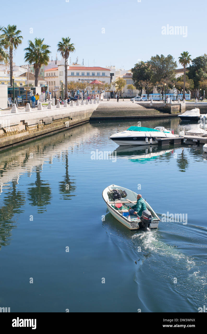 A fisherman steers his boat within the marina at Faro, Algarve ...