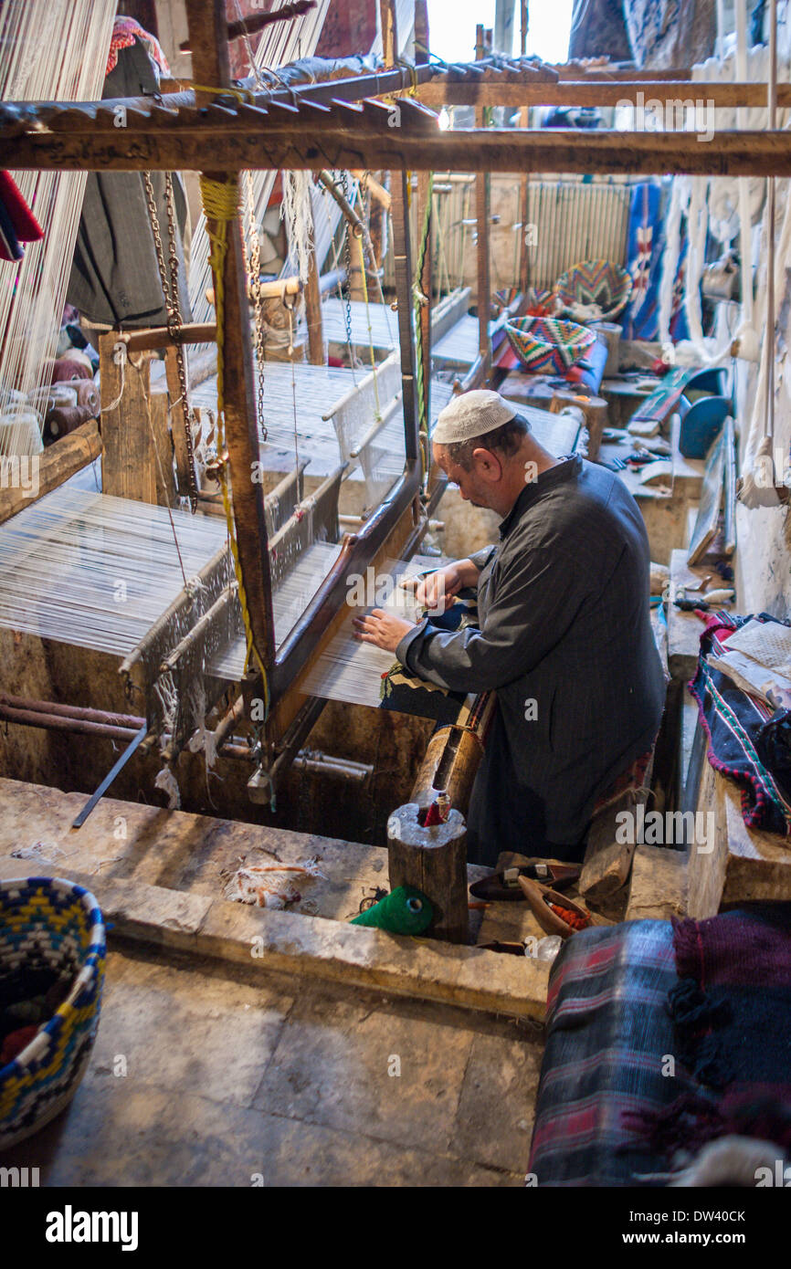 Rug weaver working in a pit loom in the central market of Aleppo, Syria ...