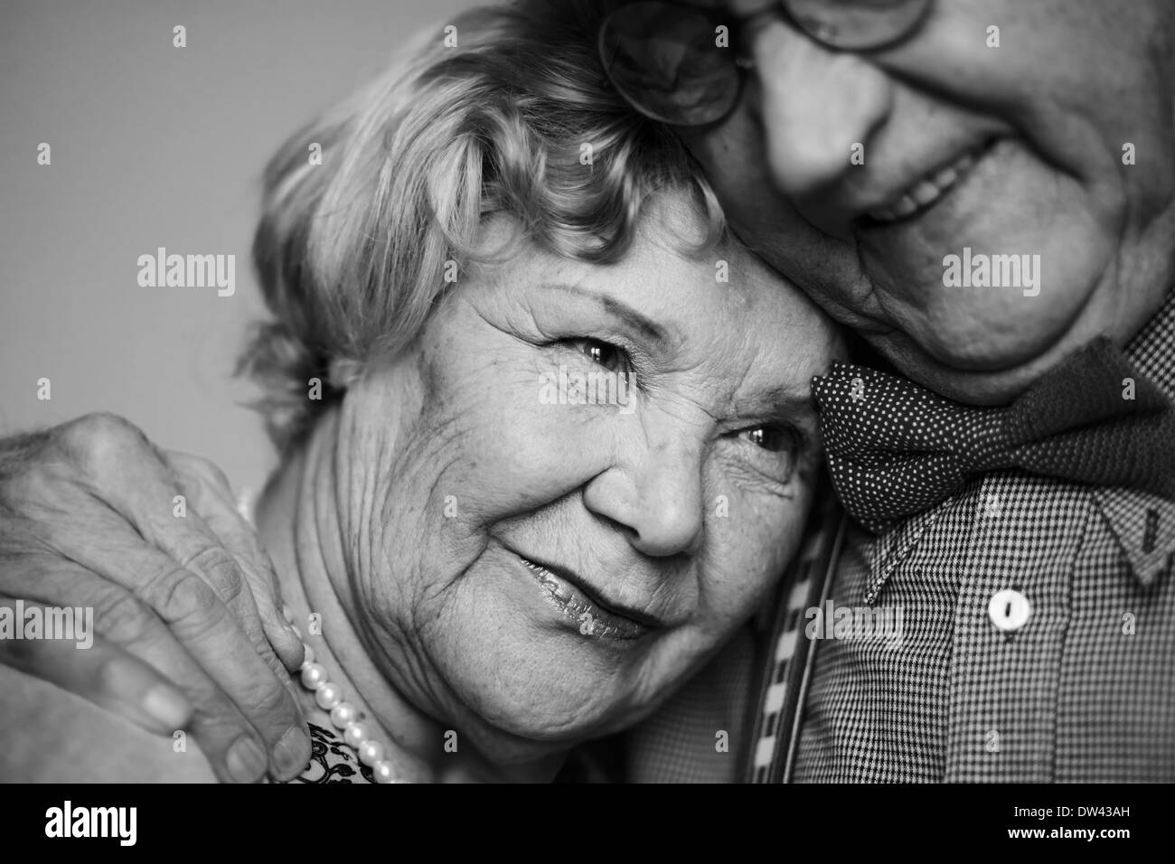 Black-and-white image of senior female being embraced by her husband ...