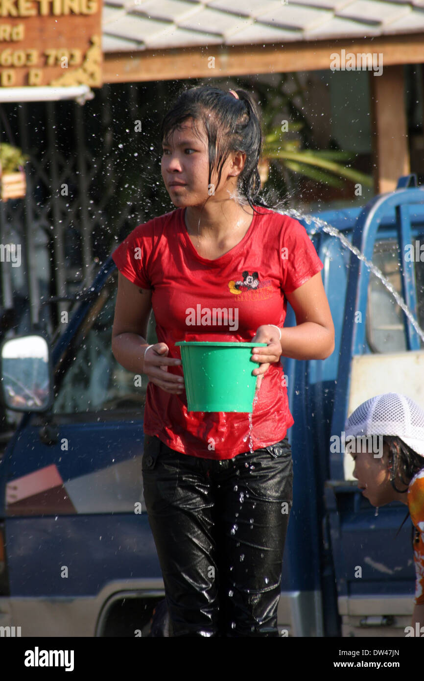 A woman is holding a bucket as she prepares to throw water at passersby ...