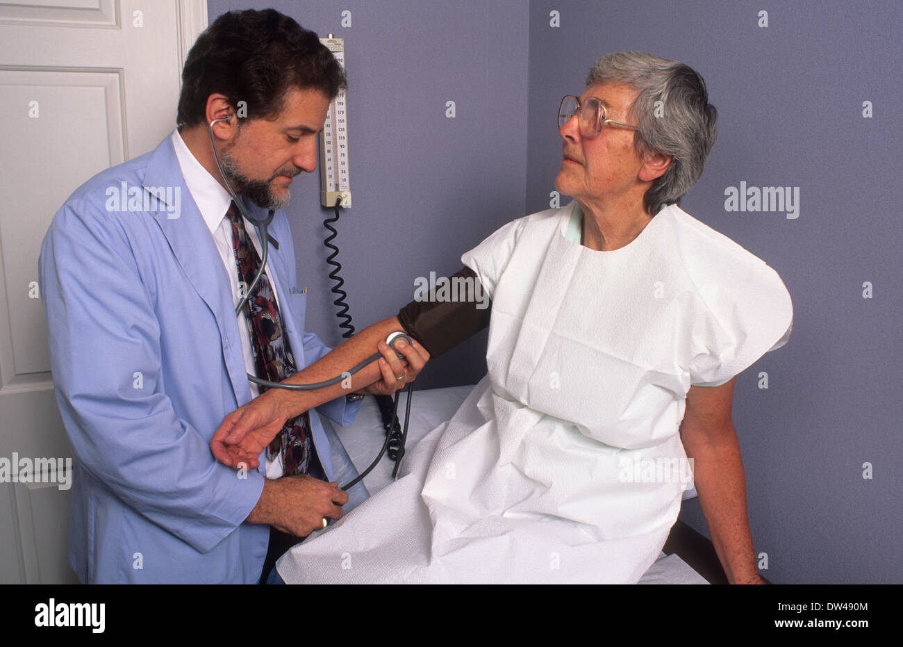 Doctor in office giving blood pressure test to older female patient in ...