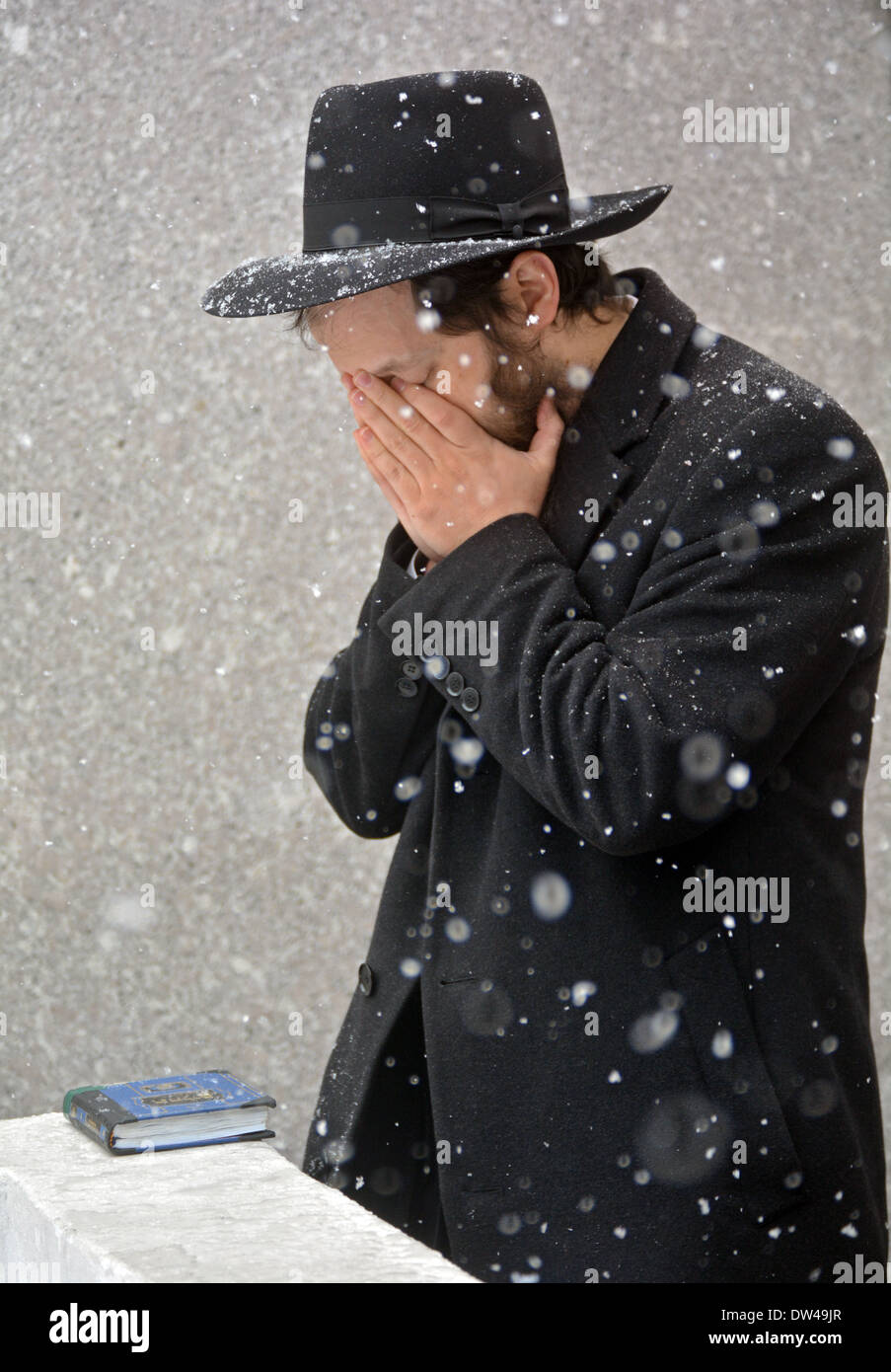 Religious Jewish man praying in the snow while visiting the grave of ...