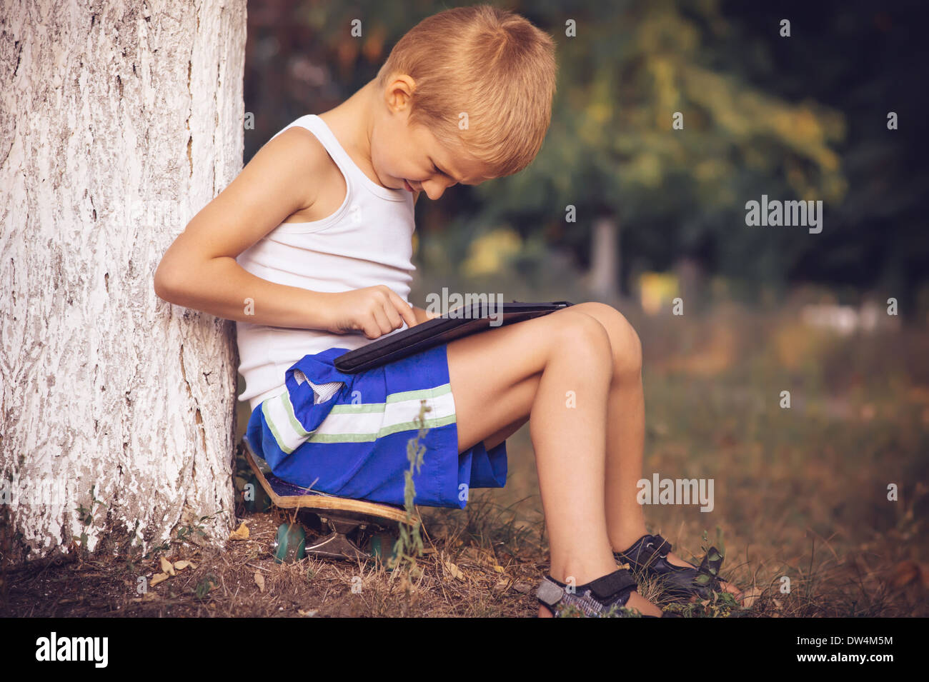 Boy Child playing with Tablet PC Outdoor with Summer nature on ...