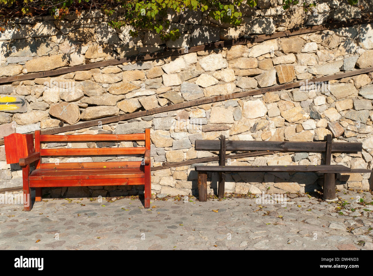 Two benches in front of a stone wall Stock Photo - Alamy