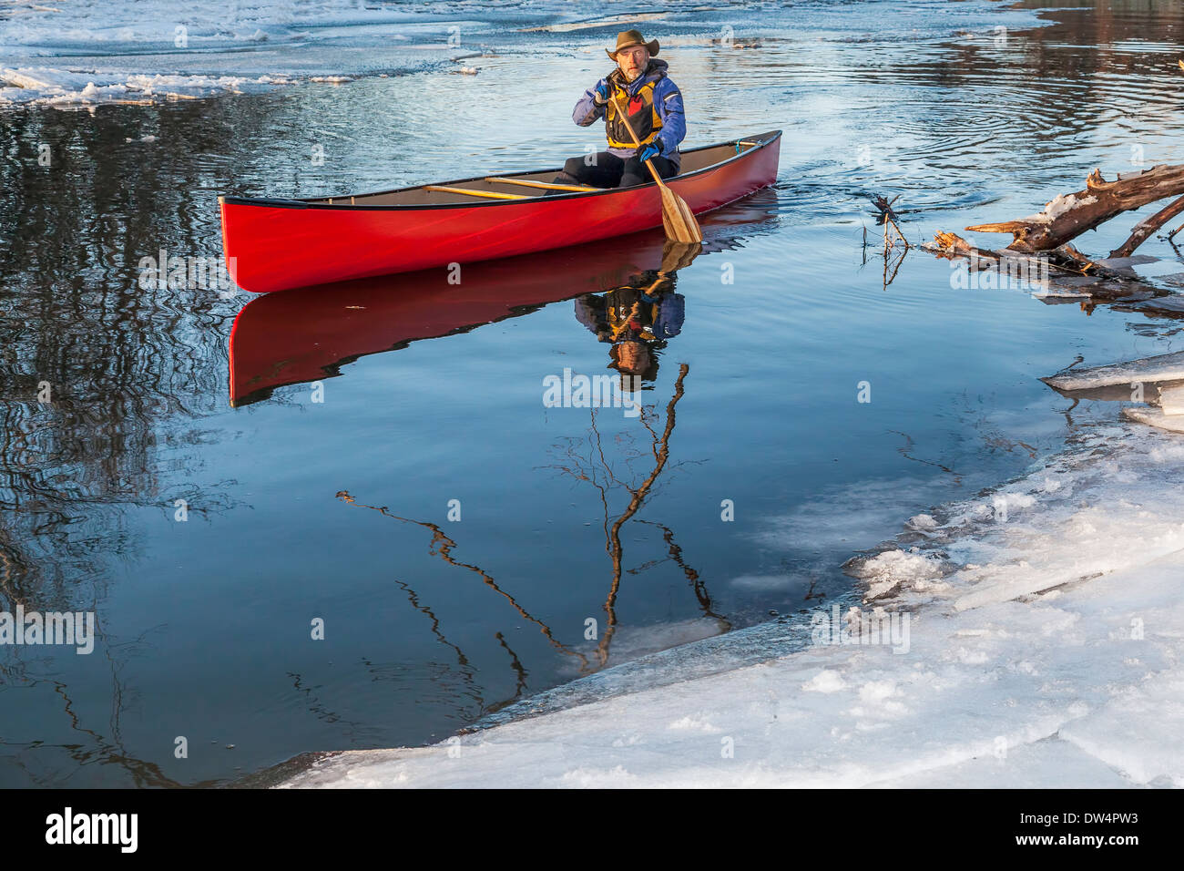 a senior male paddling a red canoe in winter - Cache la Poudre River in ...