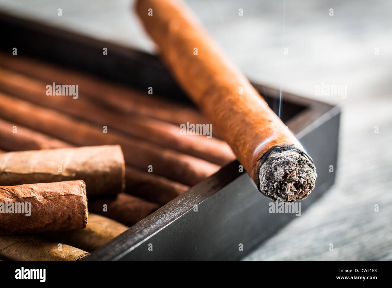 Burning cigar with smoke on wooden humidor Stock Photo - Alamy
