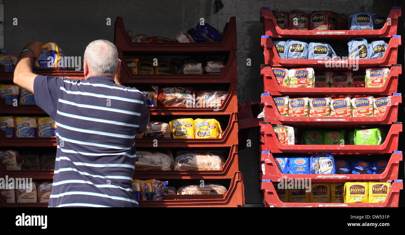 a delivery man unloads loaves of packed baked bread from the back of a ...