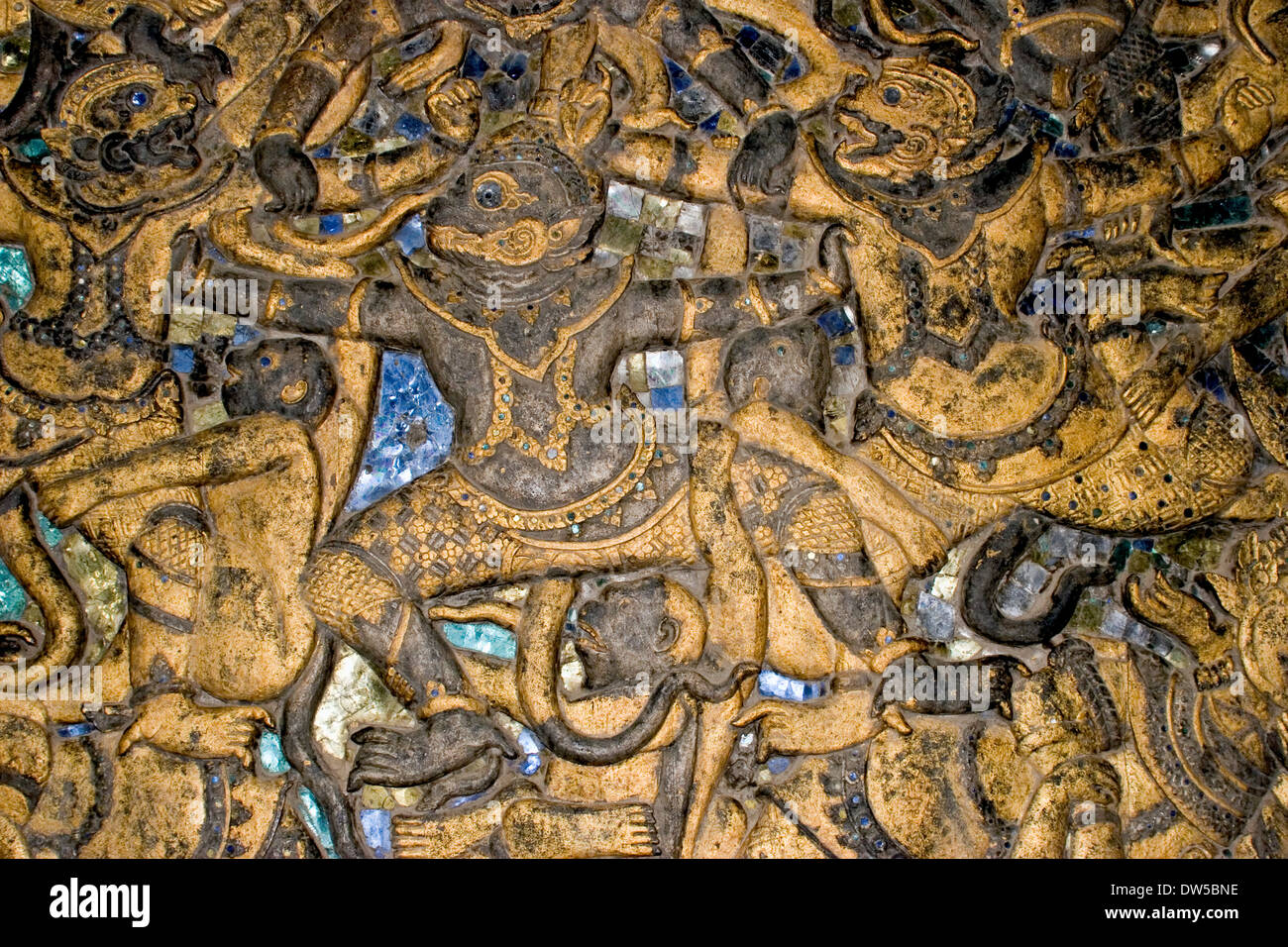 An ornate and detailed gold Buddhist wall relief sculpture adorns a ...