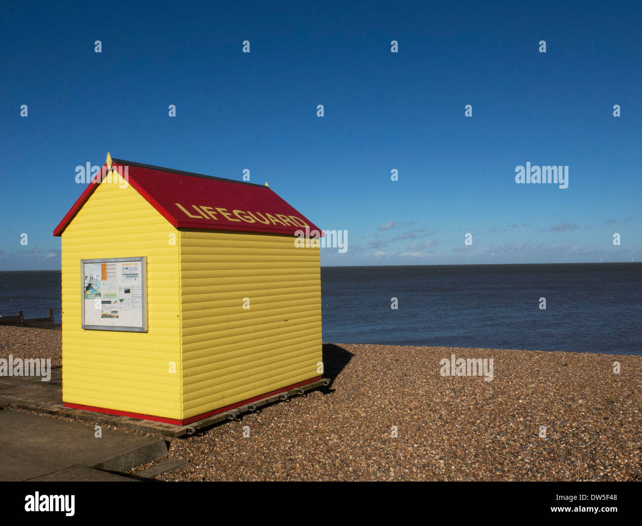 Yellow and red lifeguard hut by the sea on a blue sky day at Whitstable ...