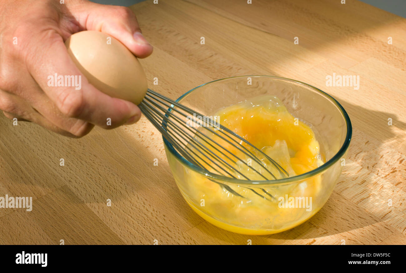 Whisking eggs in a glass bowl using a hand balloon whisk Stock Photo ...