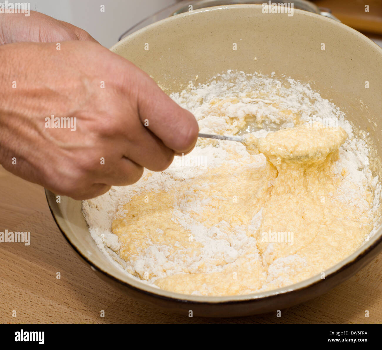 Mixing in flour to creamed ingredients in a bowl for a sponge cake ...
